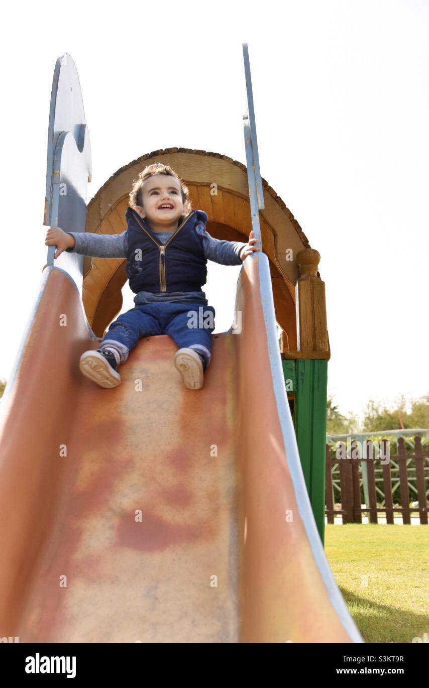 a child boy on a slide looking up and smiling Stock Photo - Alamy