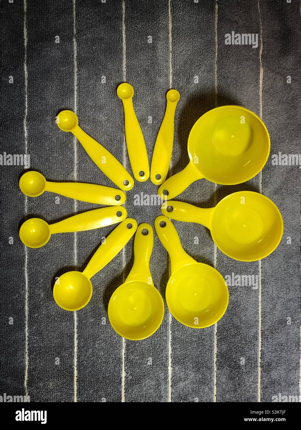 Yellow measuring cups, tablespoons and teaspoons lying down on a gray ...