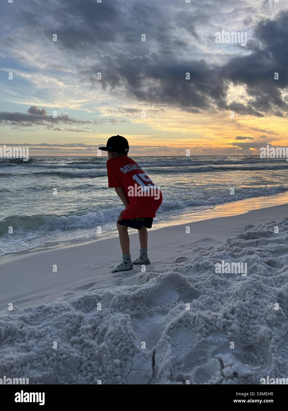 Young boy watching sunset on the beach Stock Photo - Alamy