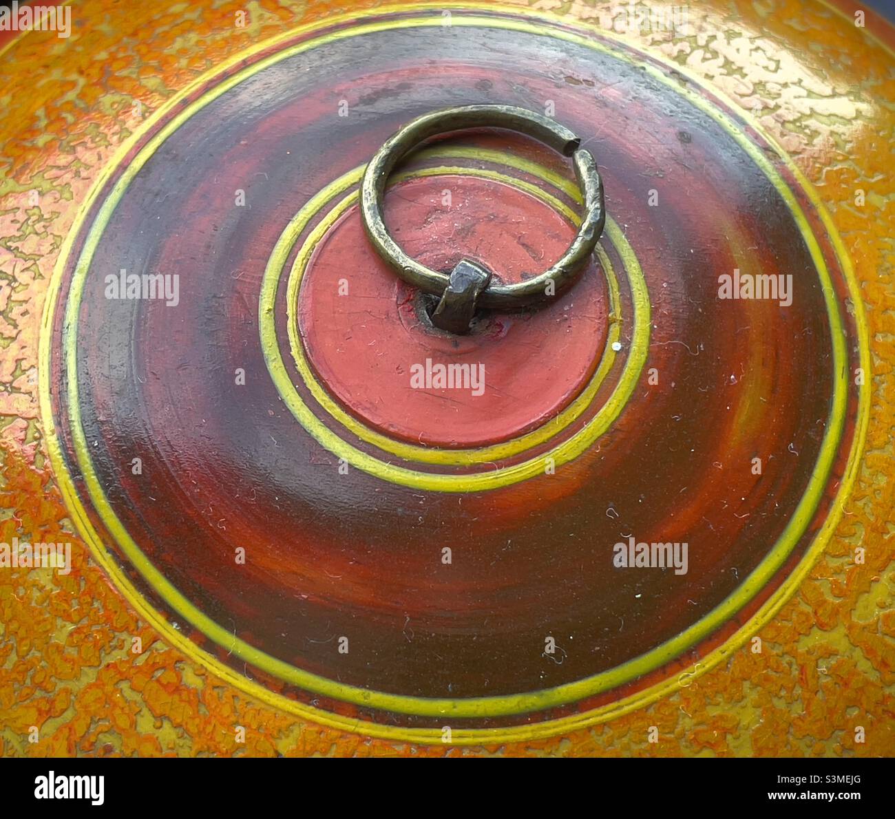 A detail of an Indian turban box with ring handle and circular painting ...