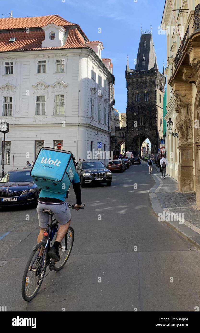 A Wolt bicycle courier in historic centre of Prague, the powder tower ...