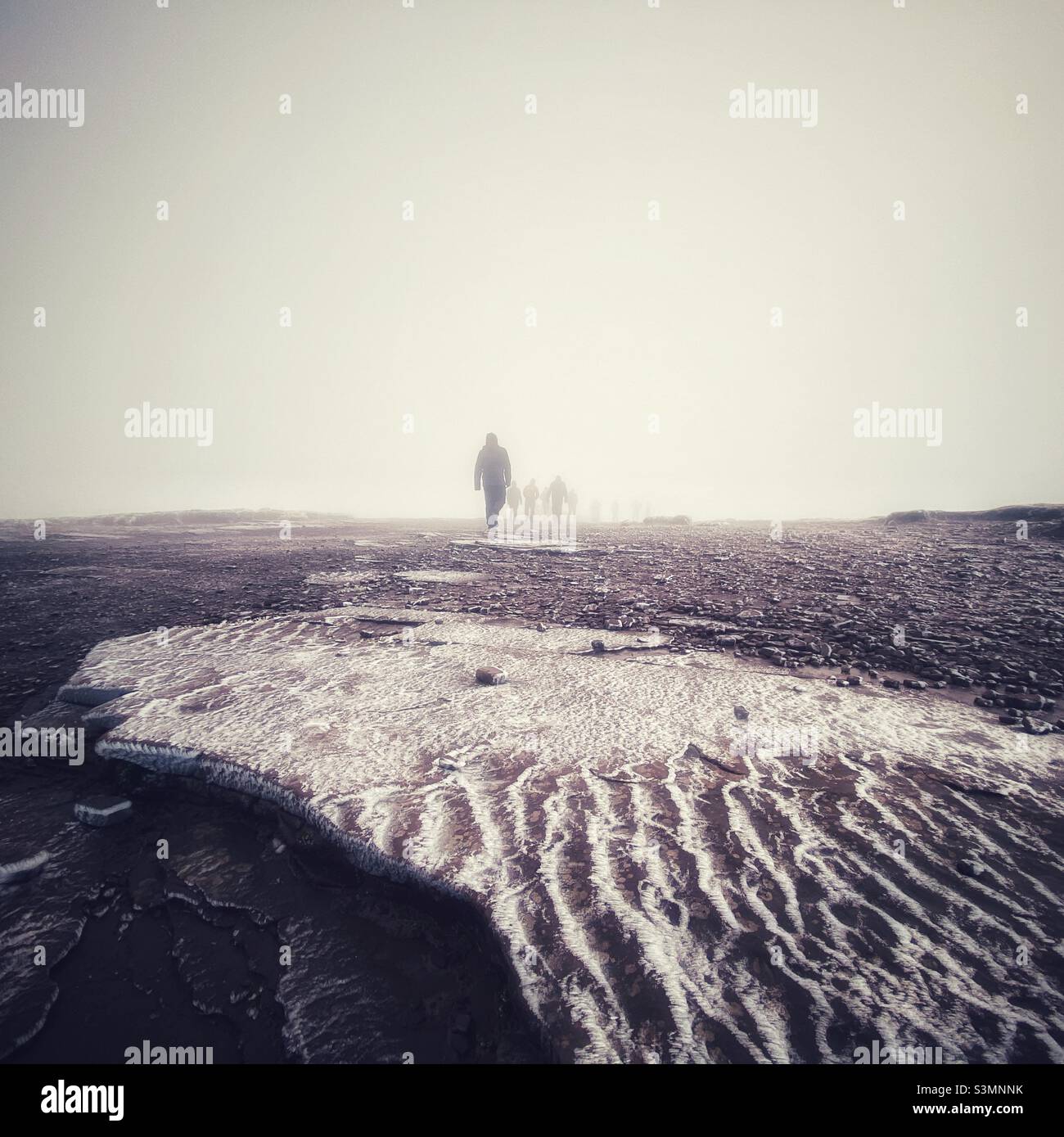 A photograph of walkers and hikers walking into fog on a frozen winter ...