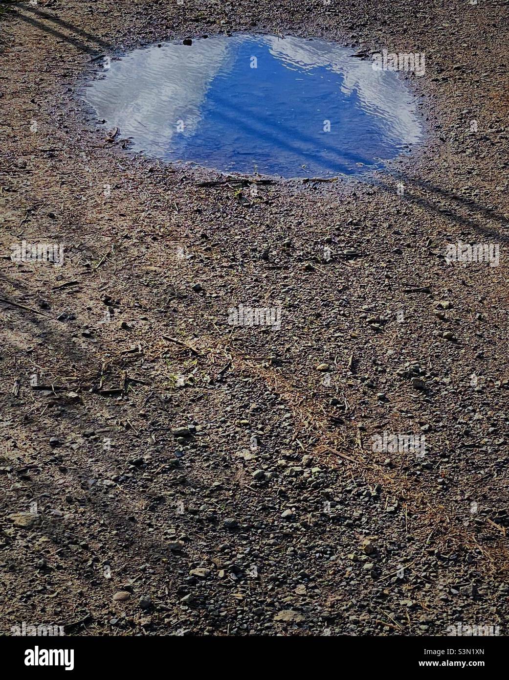 Abstract puddle; blue sky and clouds reflection, looking like planet ...