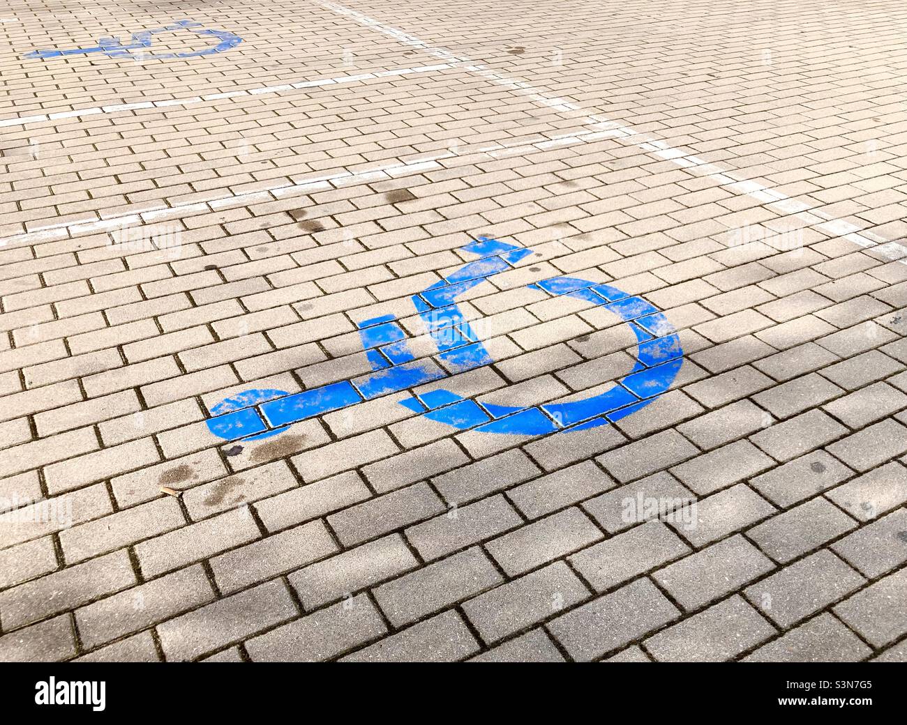 Blue painted disabled parking sign on block stone paving Stock Photo ...