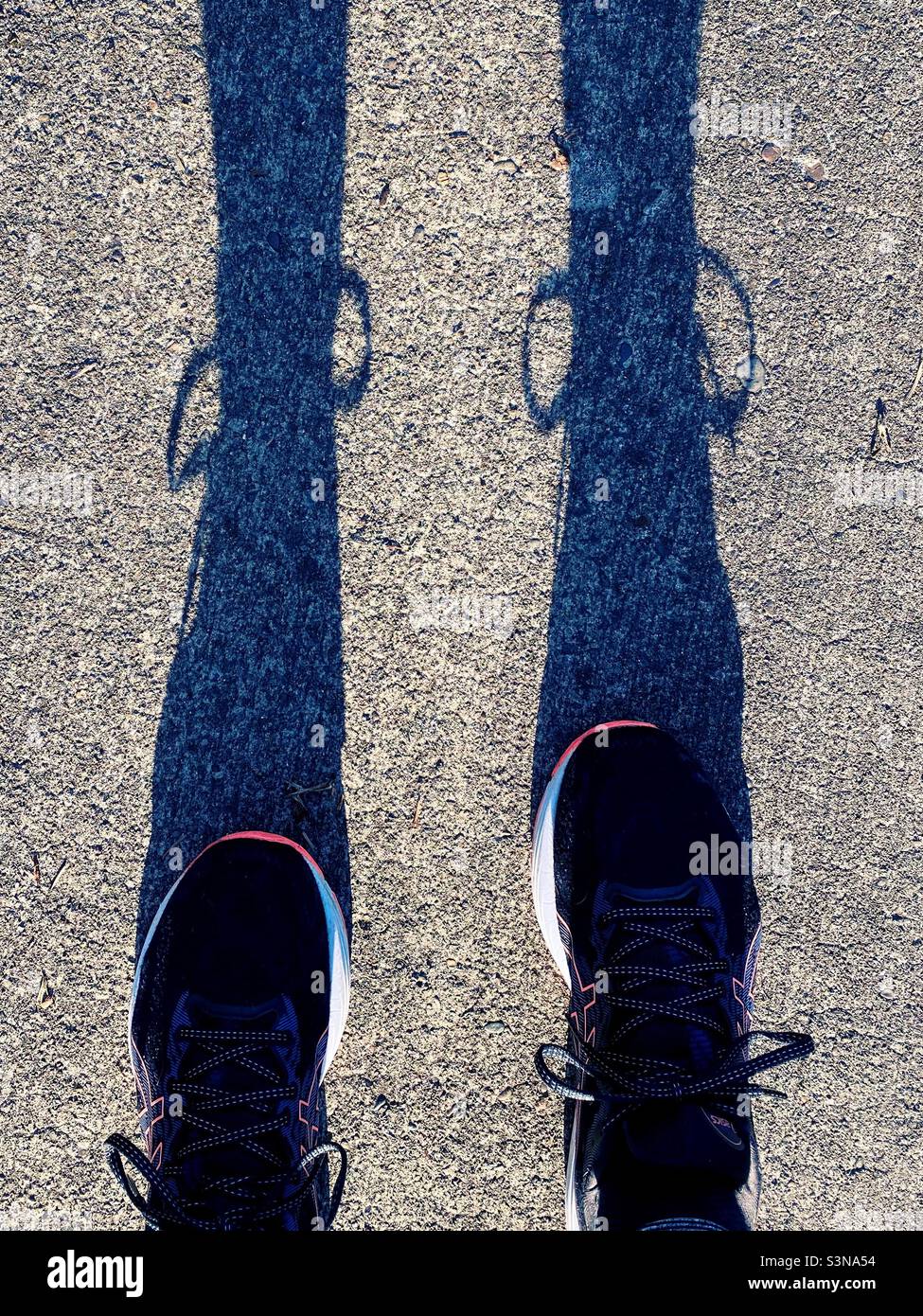 Shadow of person's feet in running shoes Stock Photo - Alamy