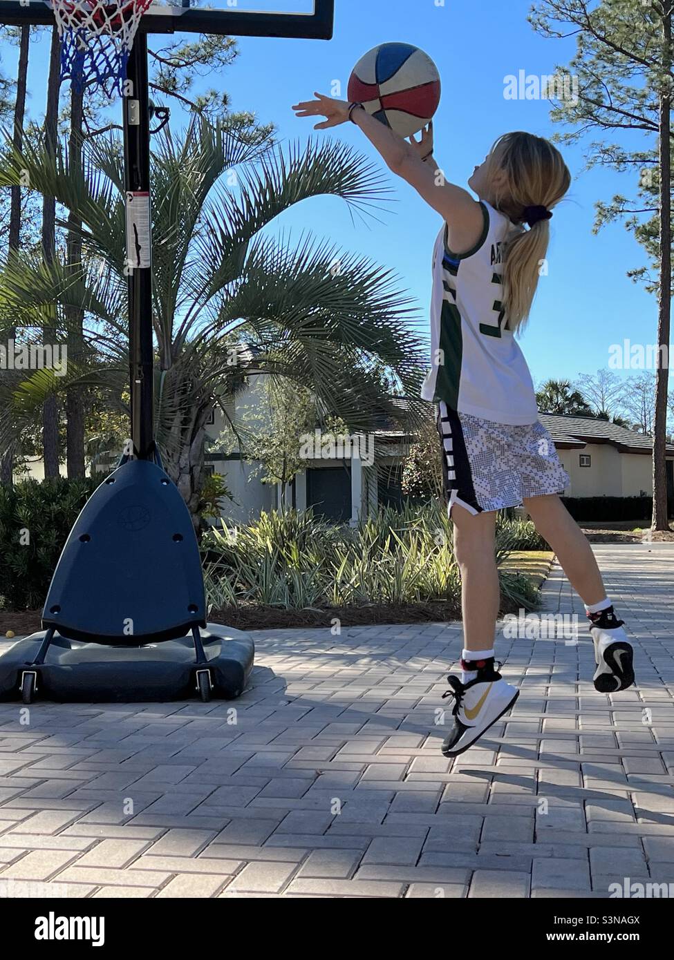 Young girl jumping to shoot a basketball Stock Photo - Alamy