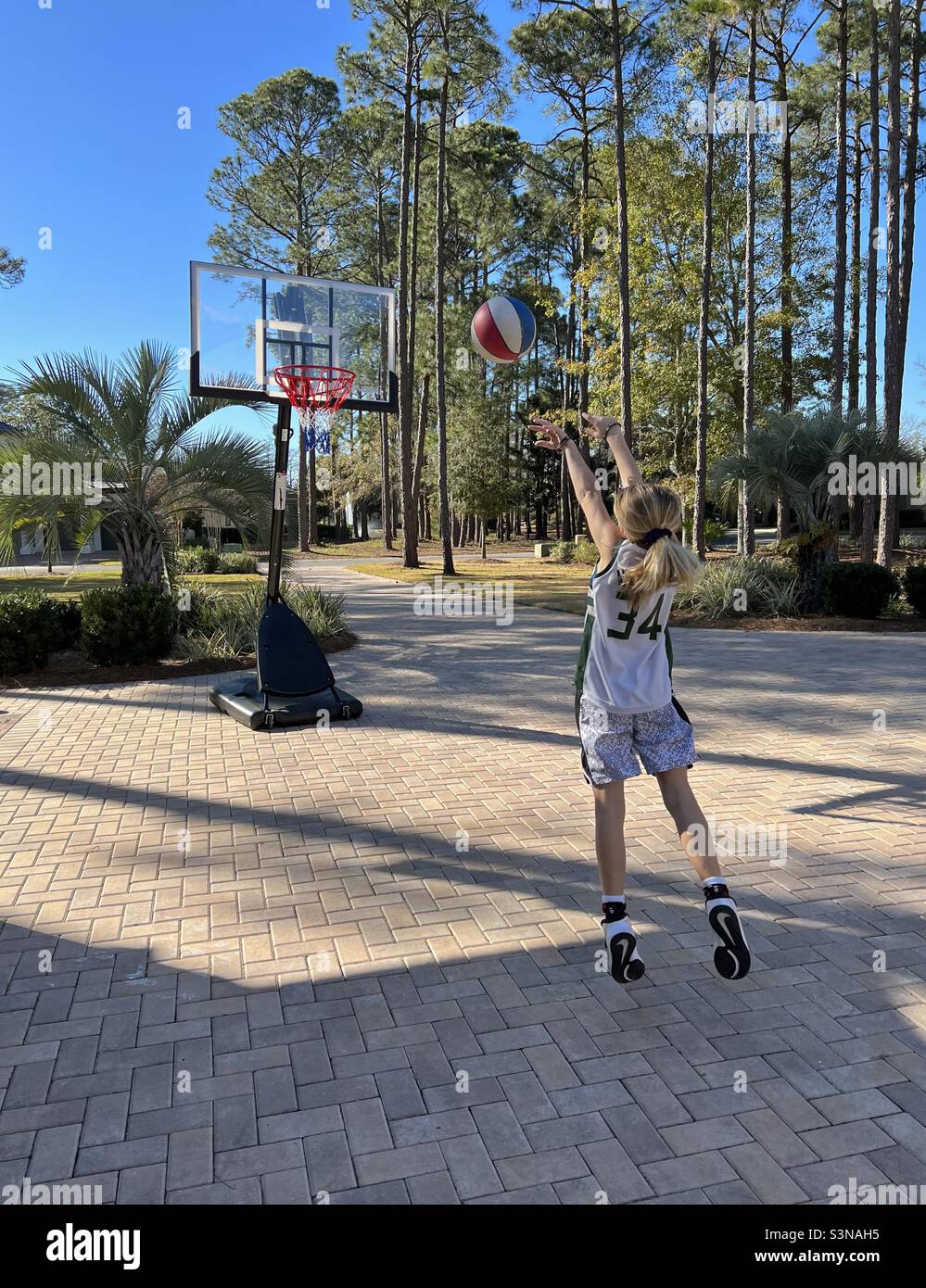 Young girl jumping high shooting a basketball at basketball hoop Stock ...