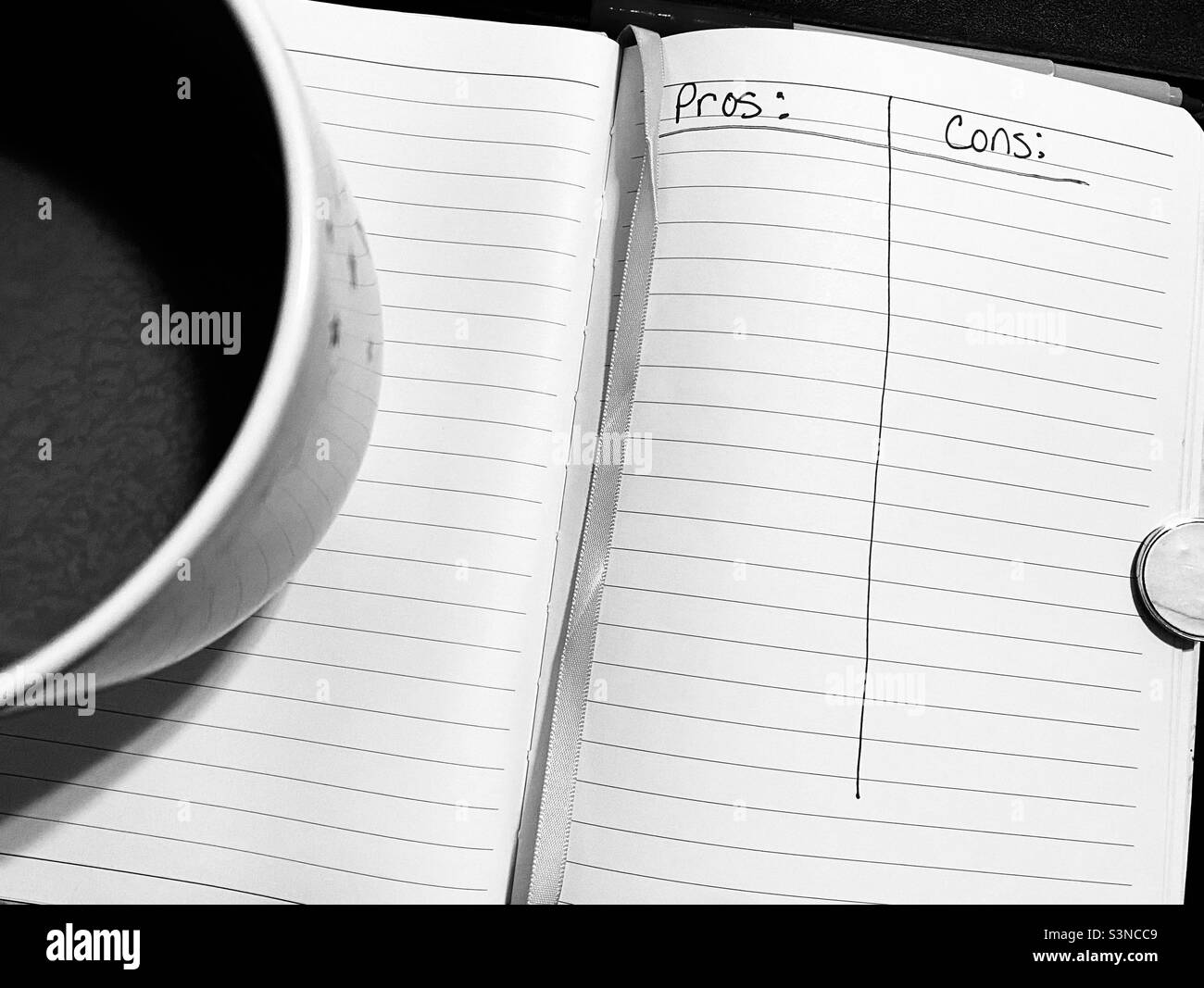 Black and white shop of open lined notebook with pro con list started ...