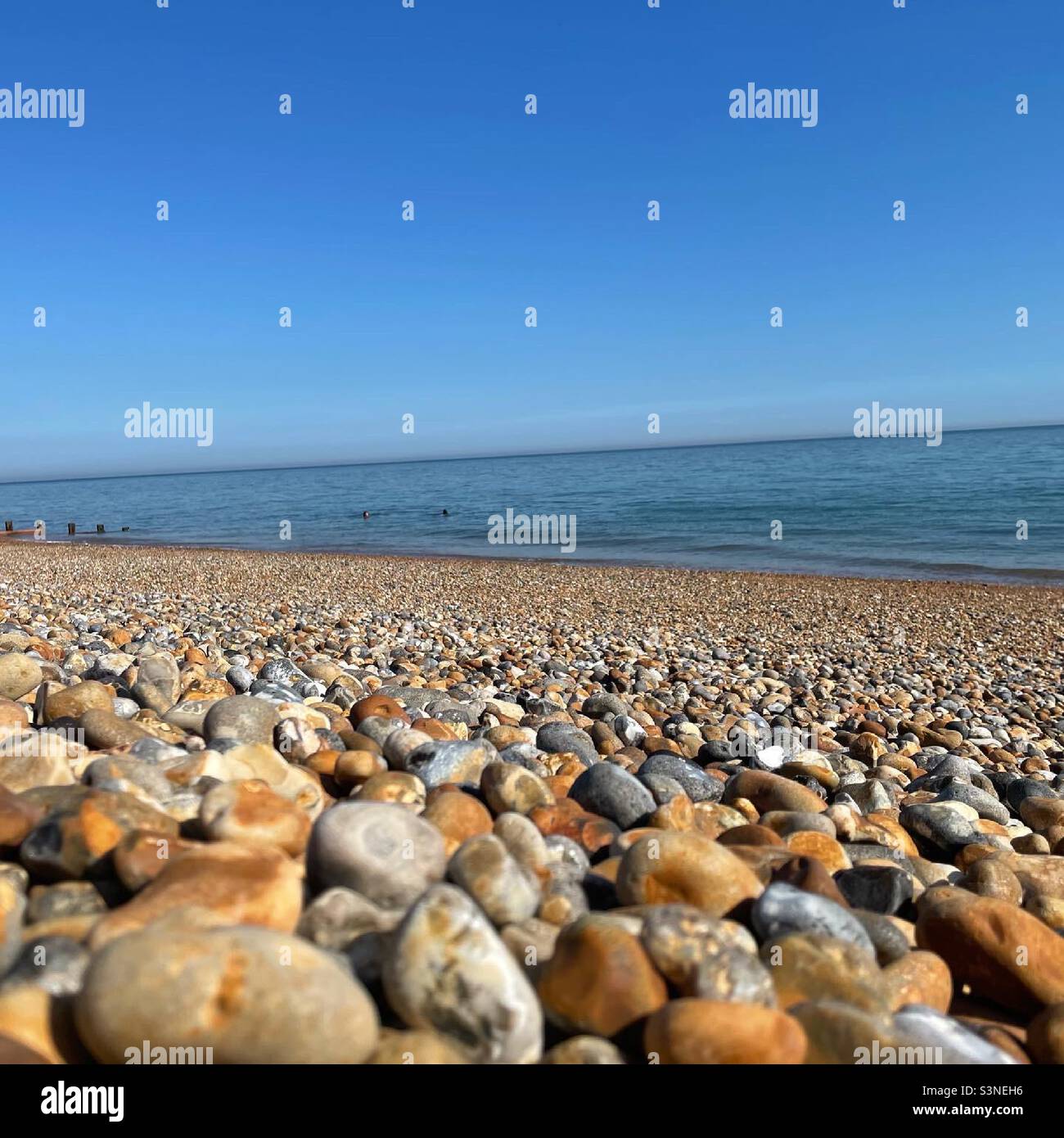 Pebbly beach close up with waves lapping at the shore on a summers day ...