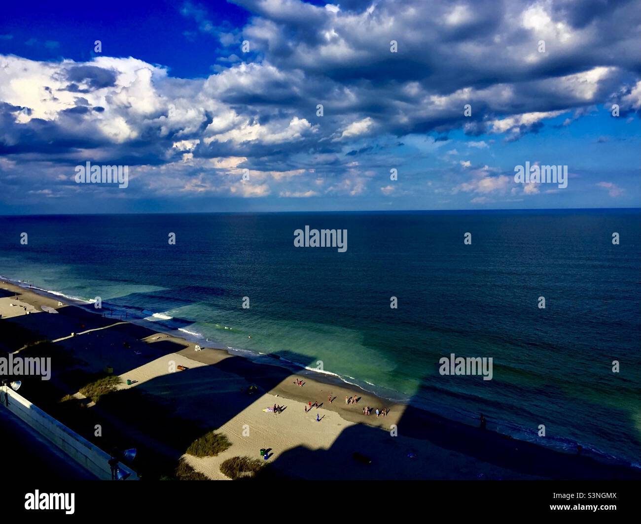 View of a beach and ocean from a balcony showing sunlight and shadows ...
