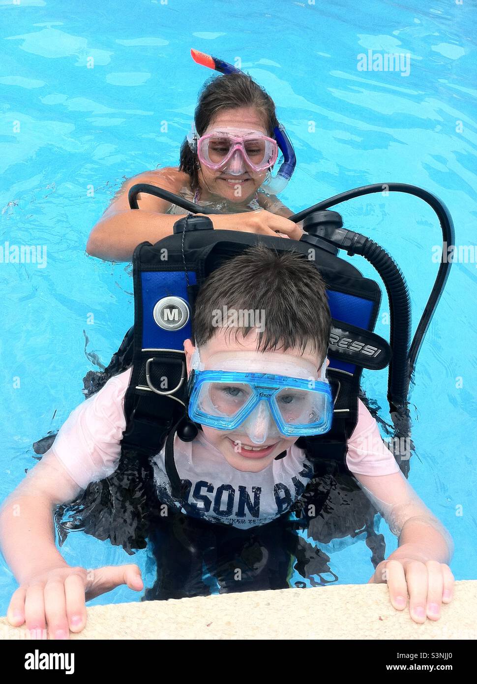 Young boy learning how to scuba dive, his instructor checks his ...