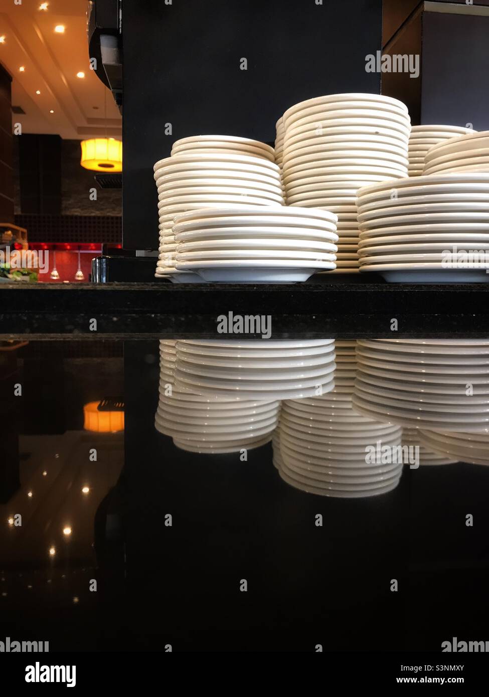 Buffet plate stack with a reflection on the table Stock Photo - Alamy
