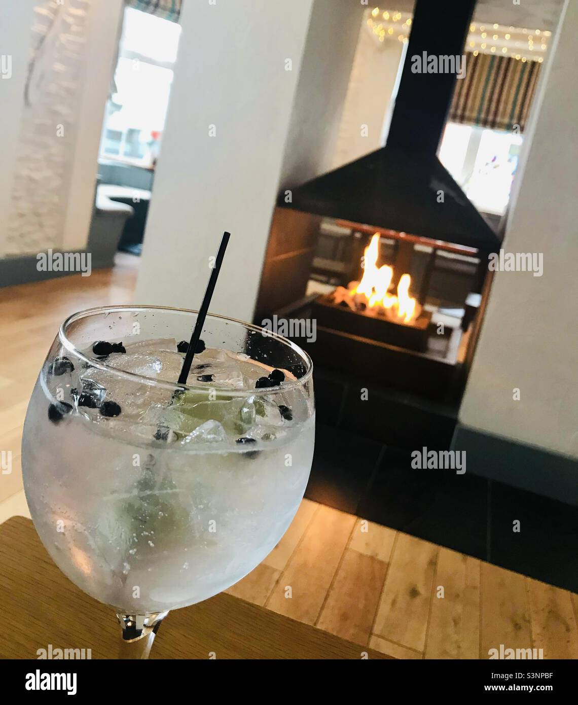 Cold glass of gin and tonic against a backdrop of an open fire Stock ...