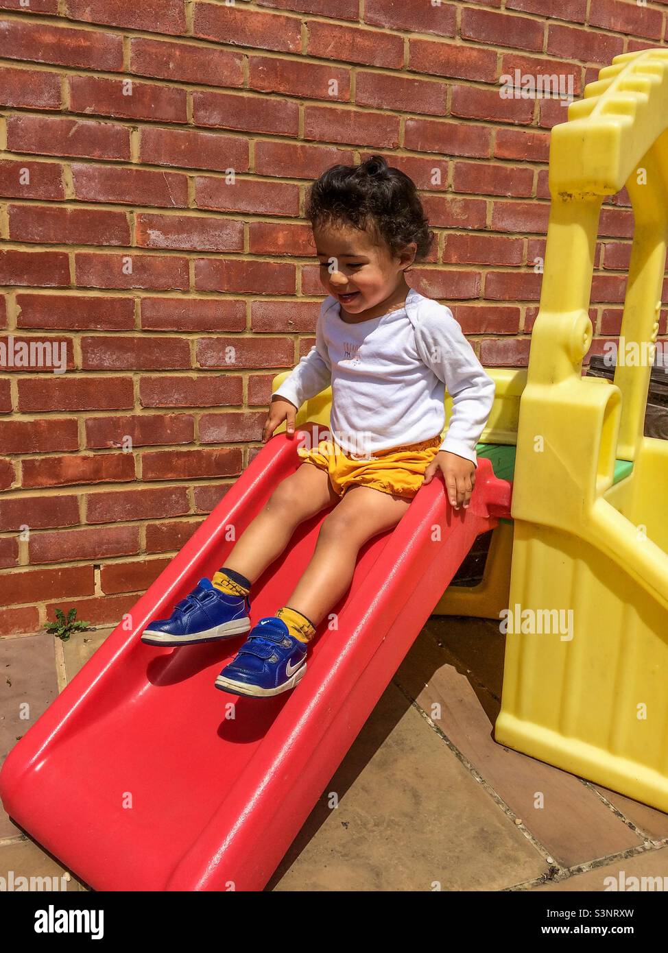 Young girl playing in a colourful toy slide Stock Photo - Alamy
