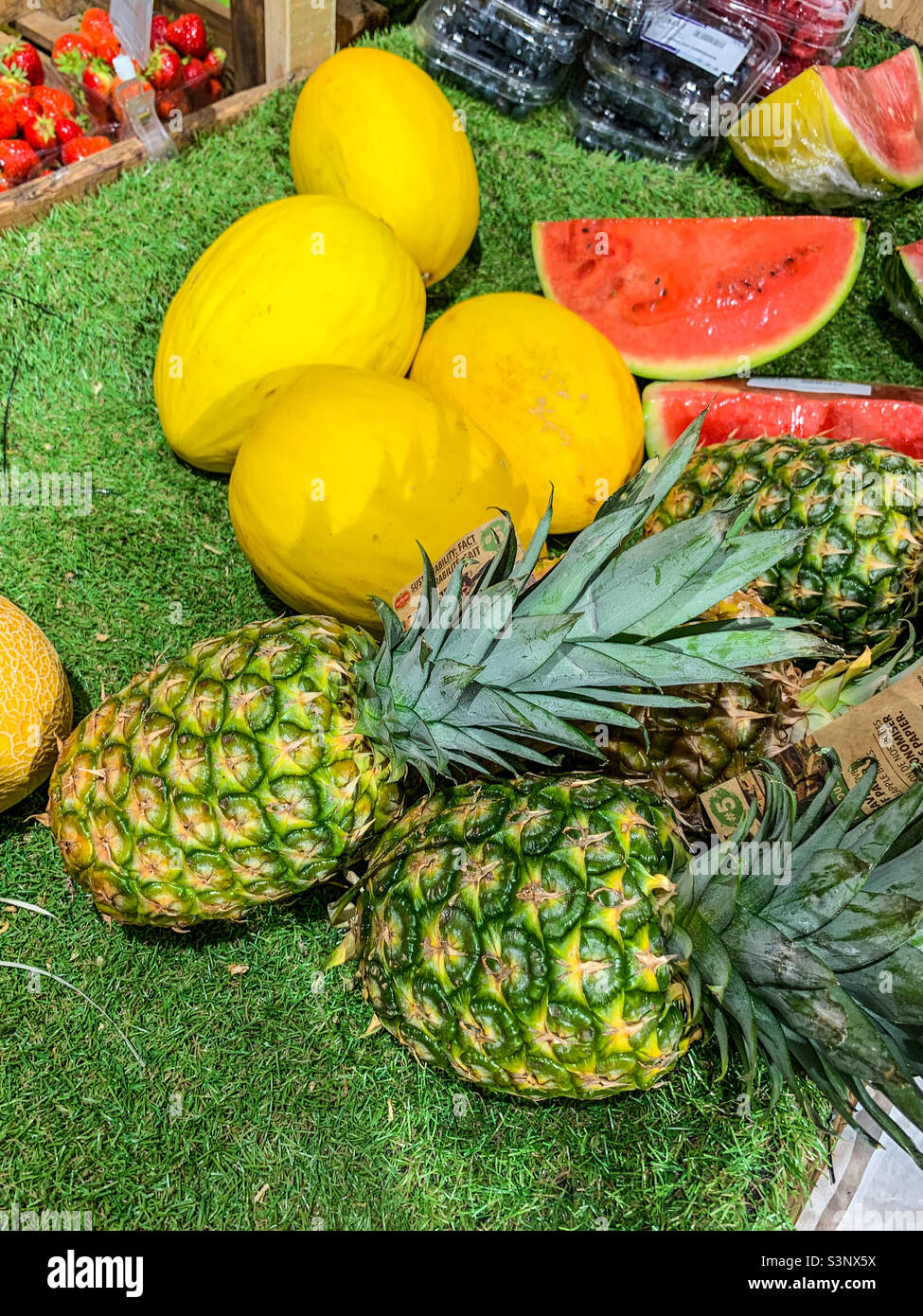 Pineapples and melons on display Stock Photo - Alamy