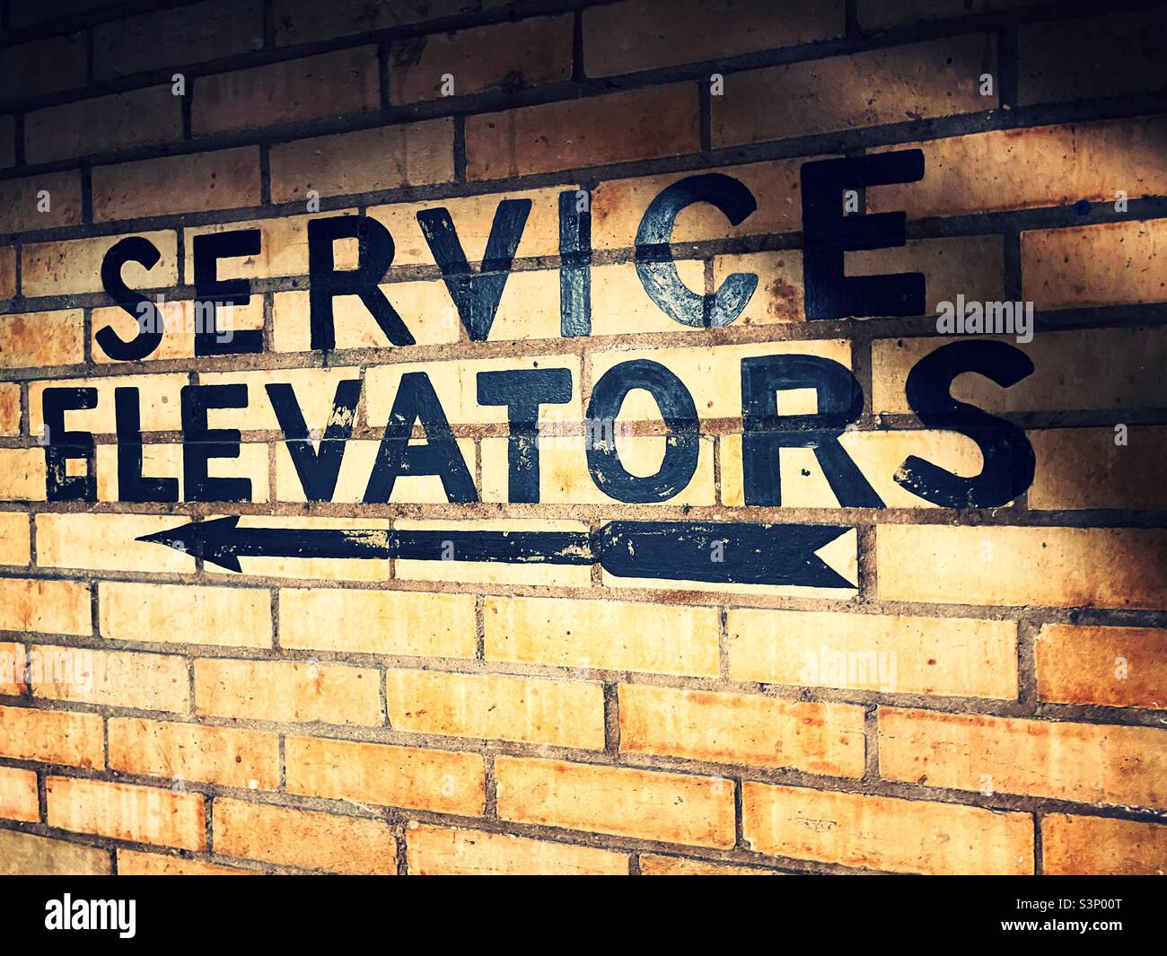 Service elevator directions sign painted on a tan brick wall in an ...