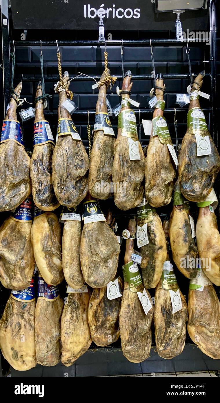 Spanish cured dried Iberico ham hanging on a rack in a supermarket ...
