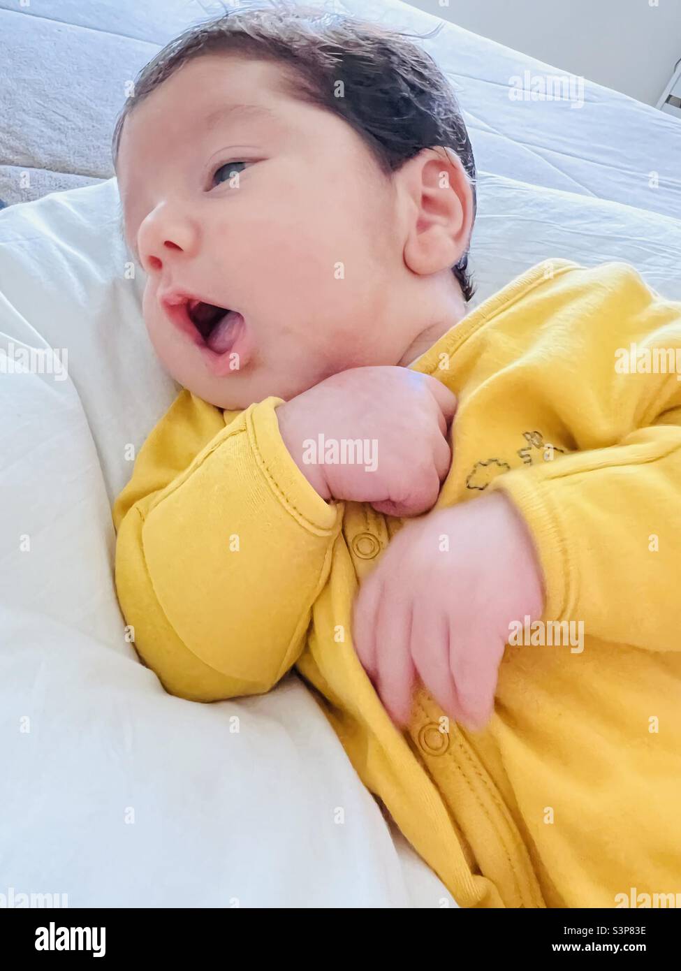 Hungry baby wearing yellow Stock Photo - Alamy