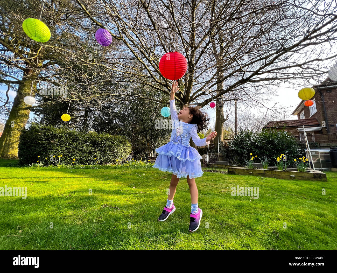 Young girl jumping to touch suspended red balloon Stock Photo - Alamy