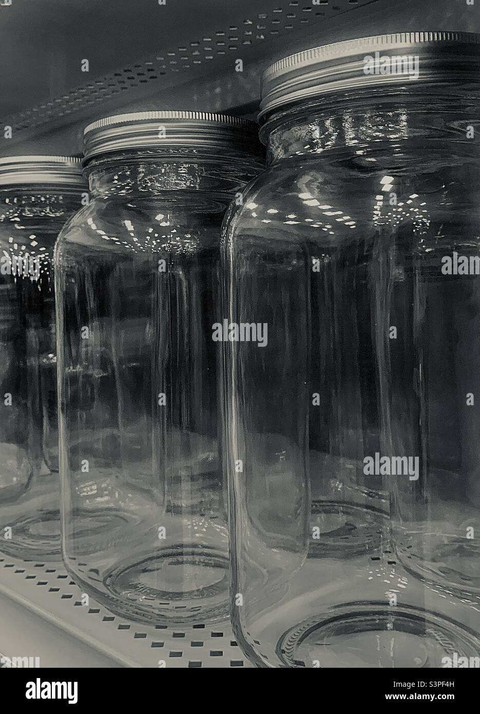3 empty glass jars with silver lids neatly displayed on metal shelf ...
