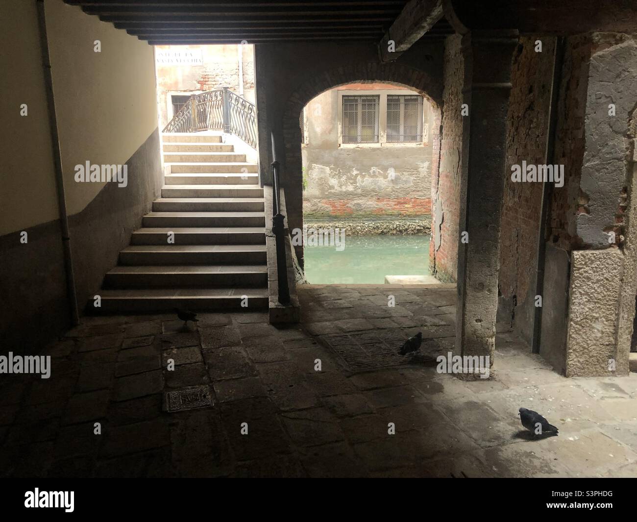 Walkthrough leading to stairs on a bridge over a canal in Venice, Italy ...