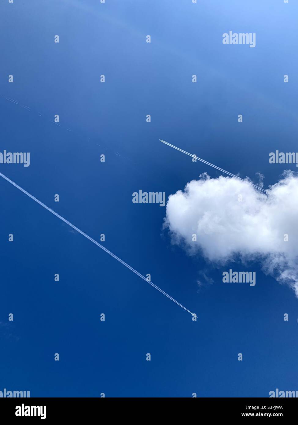 Aeroplane contrails and white cloud against blue sky Stock Photo - Alamy