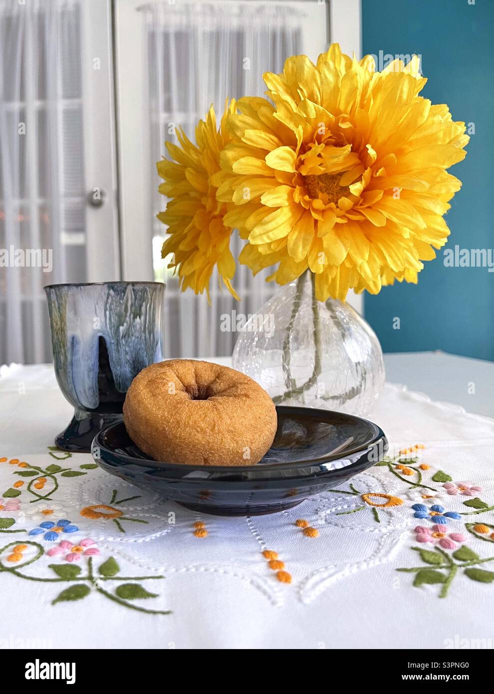 Still life with pottery, a doughnut, and flowers in a glass vase, all ...