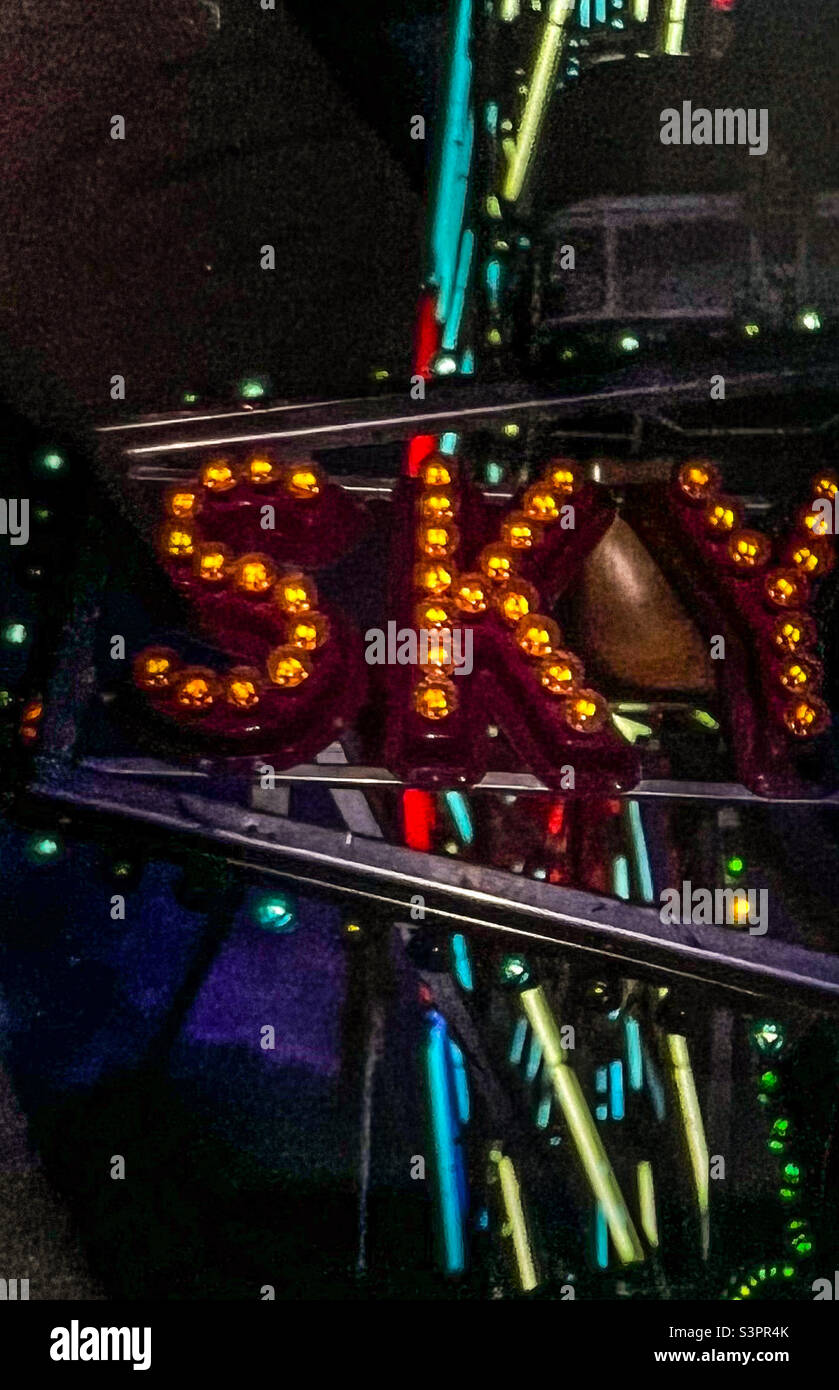 Amusement park lights on ride at night “SKY “ neon bulb lights against ...