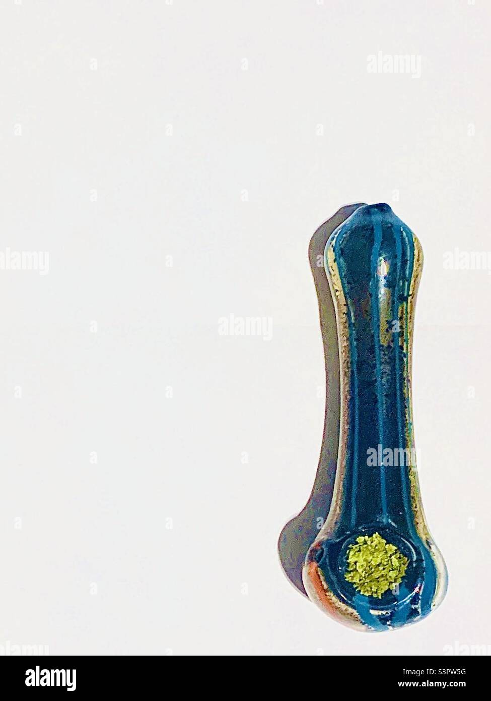 Glass Marijuana pipe with bowl full of bright green flower is shown in ...
