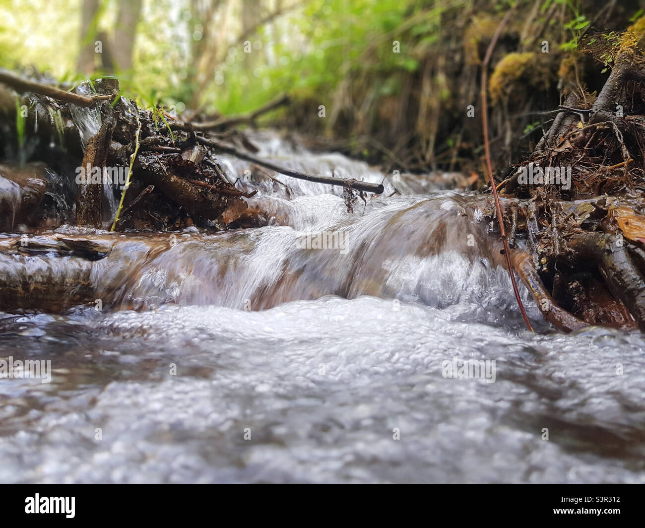 the water source flows down the rocks into the river Stock Photo - Alamy