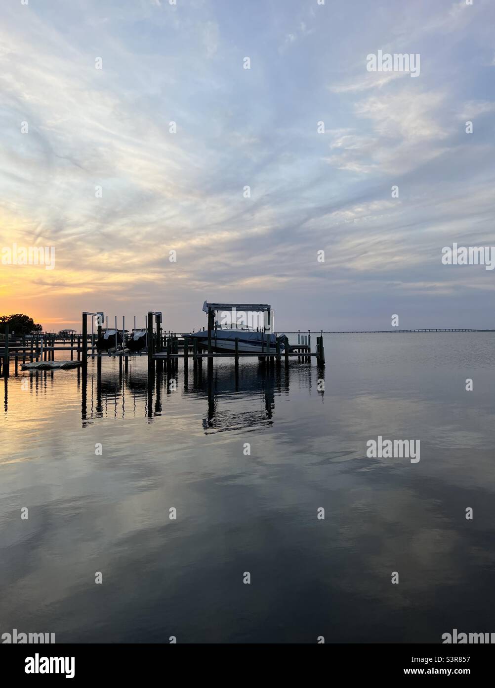 Sunset with boat docks over bay water Stock Photo - Alamy