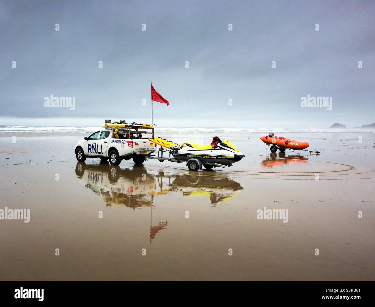 RNLI lifeguards flying red flag at Perranporth Beach, Cornwall,UK on a ...
