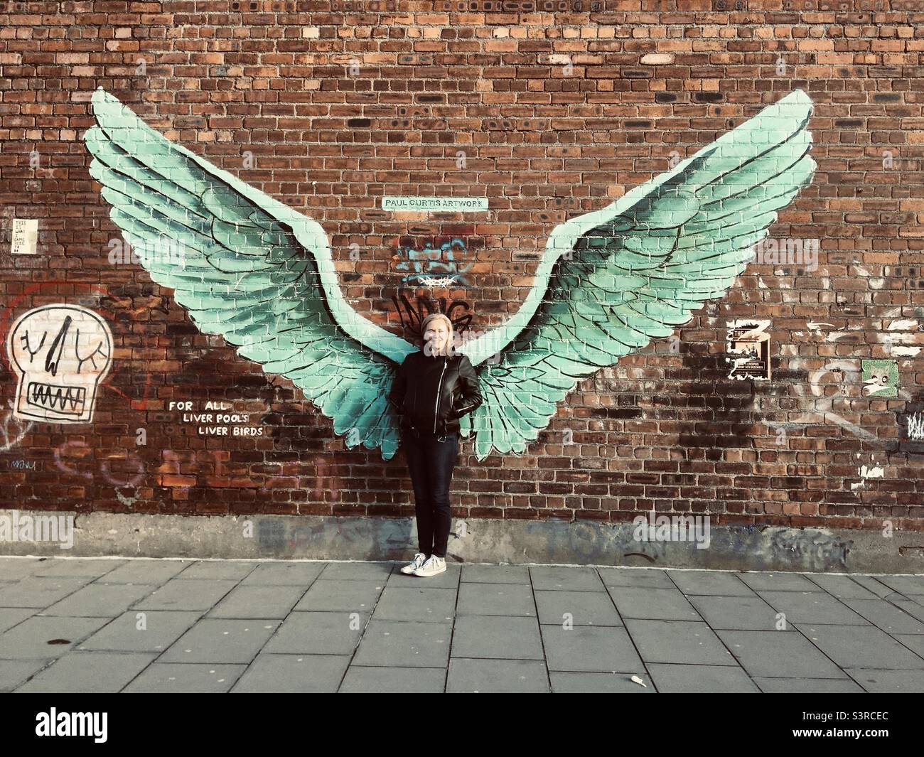 Woman standing in front of liver bird wings in Liverpool by Paul Curtis ...