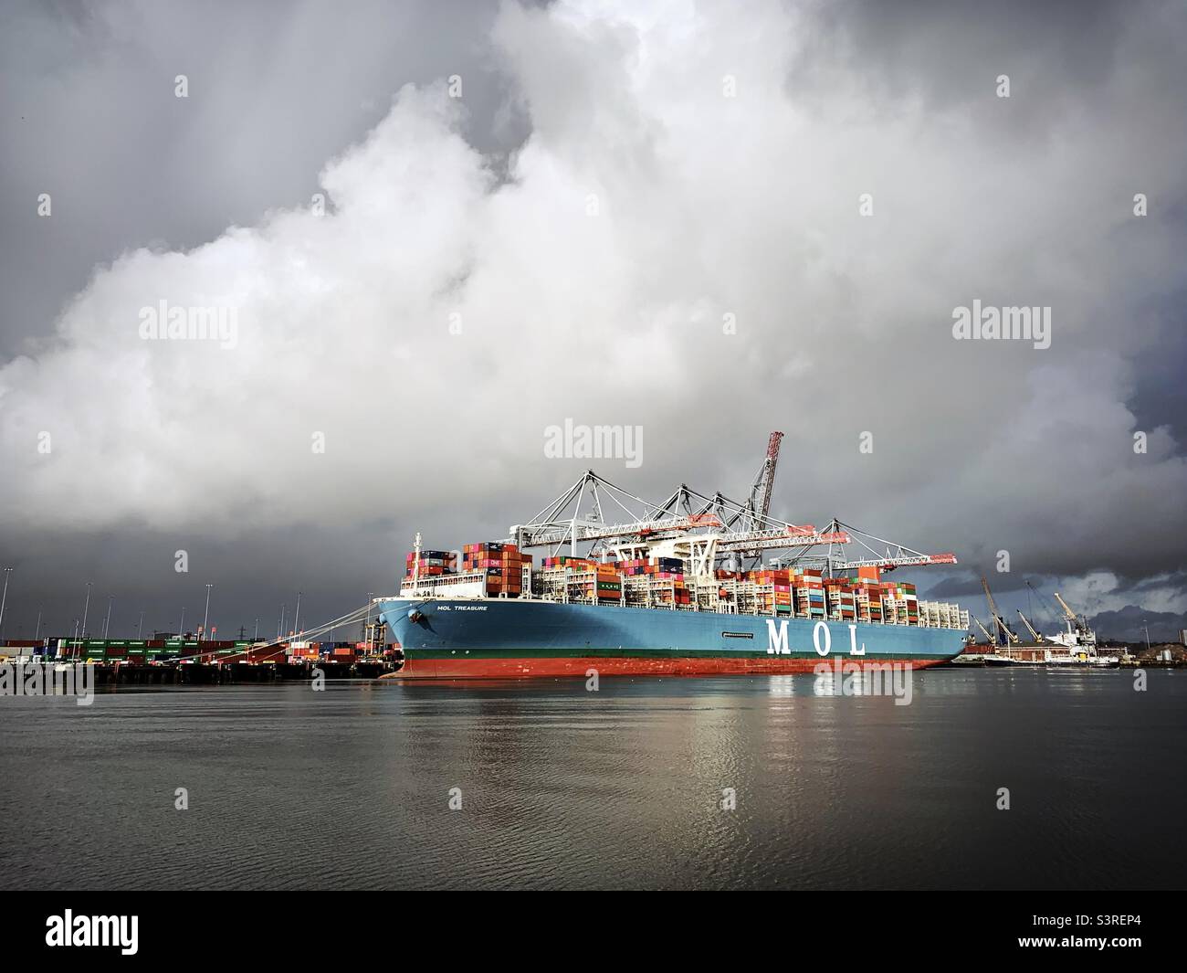 Rain clouds gather over a container ship as it’s loaded with containers ...