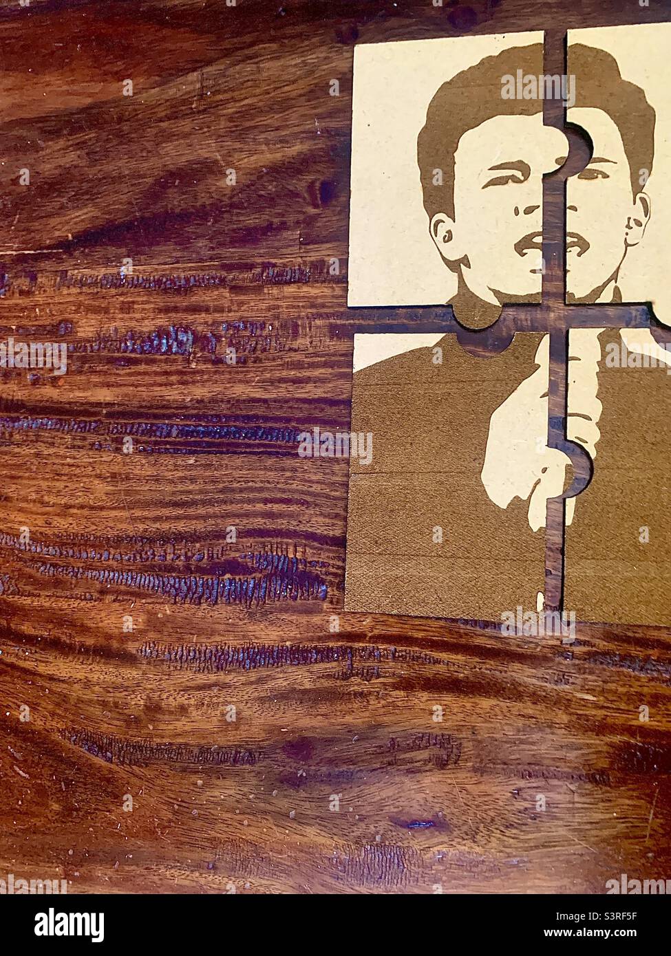 4 piece puzzle of young man’s face in top corner of wooden table with ...