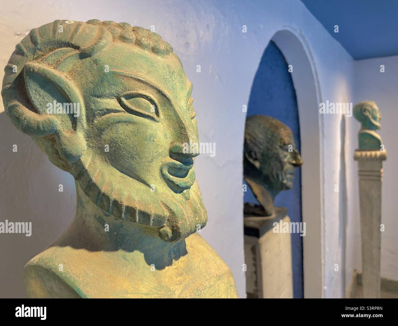 Two Greek style busts of fauns flanking a niche containing a portrait ...