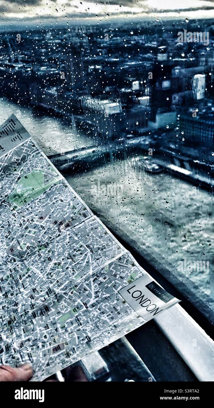 Holding a map of London from behind the rain splattered glass of The ...