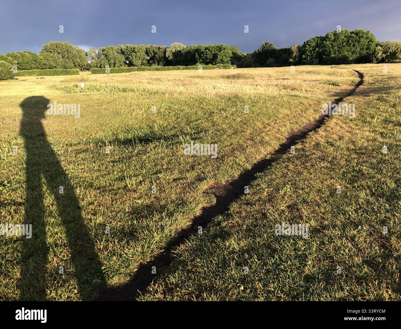 Shadow of a person and a small path on grass Stock Photo - Alamy