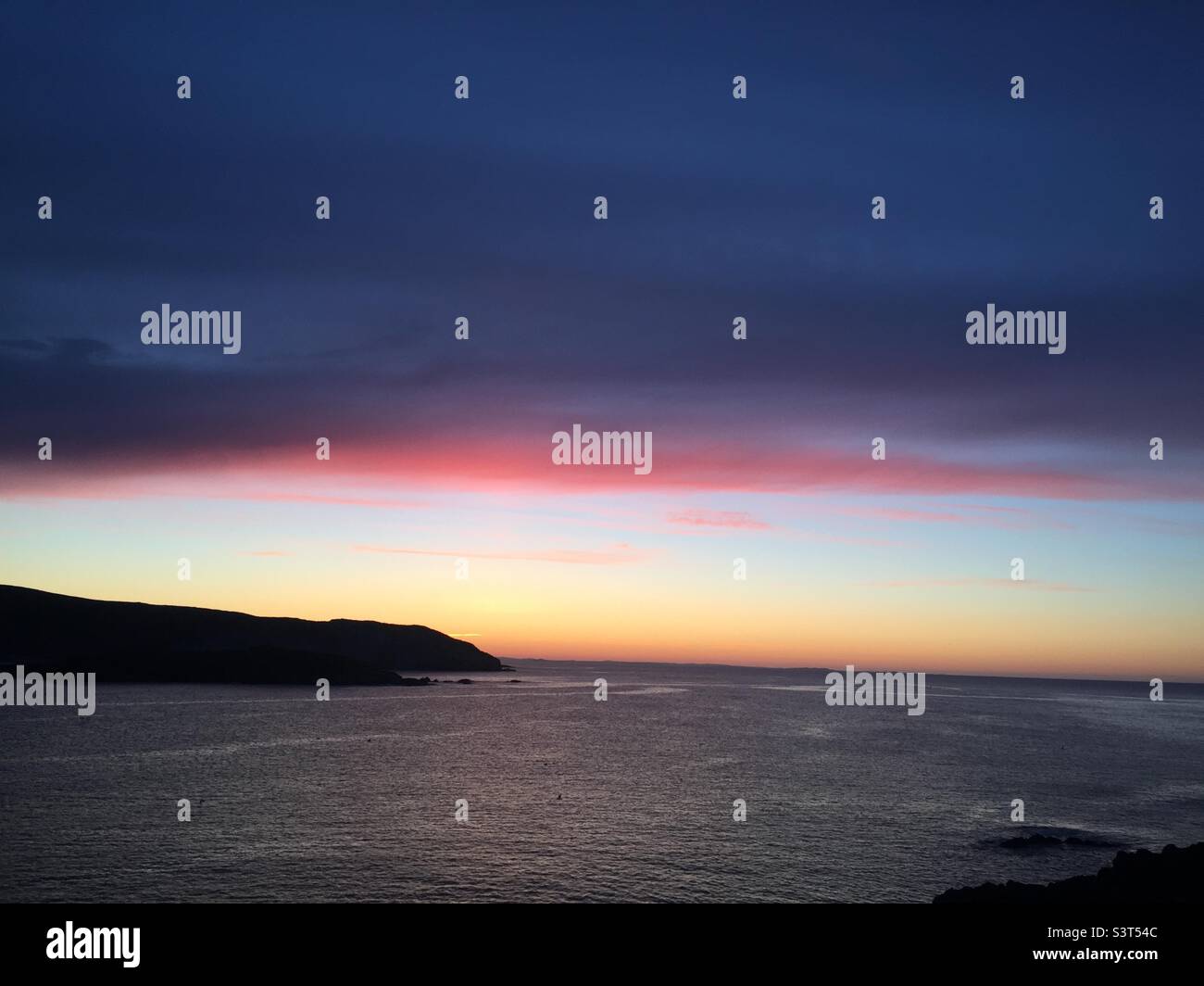 Glow along the horizon after a sunset in an Atlantic harbour with dark ...