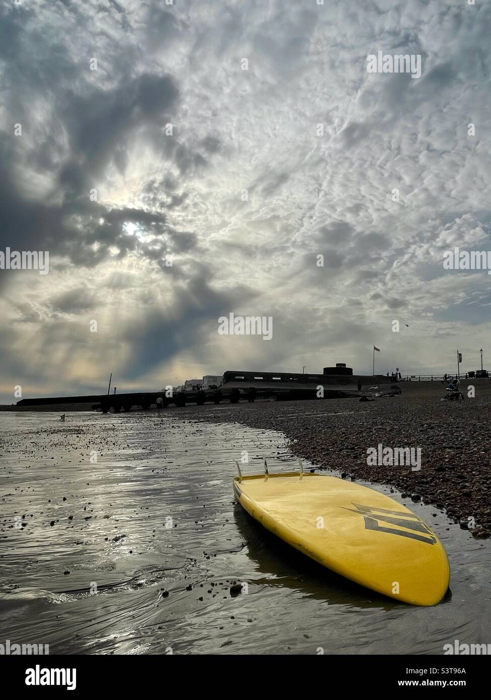 Yellow paddle board on the shore of a pebble beach near sunset Stock ...