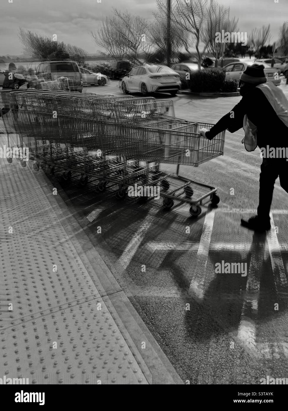 The man worker is pushing the shopping carts while the customers are ...
