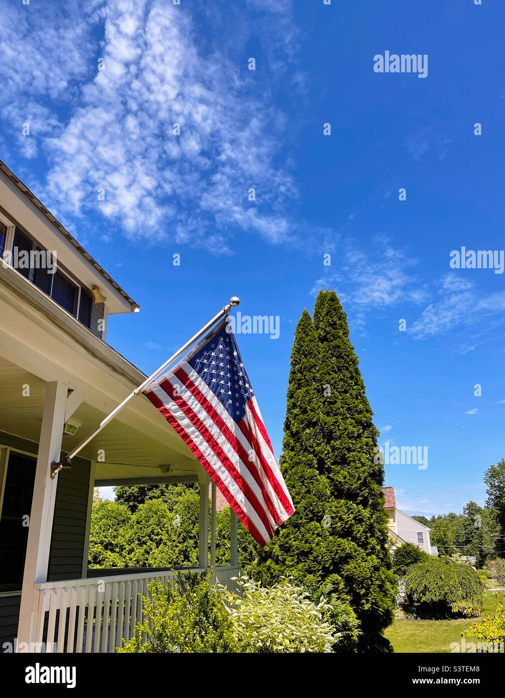 An American flag hangs in front of an upscale suburban northeastern ...