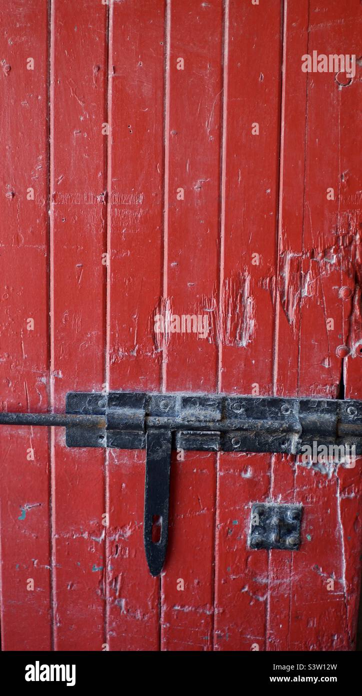 Rustic gate bolt lock on a red door Stock Photo - Alamy