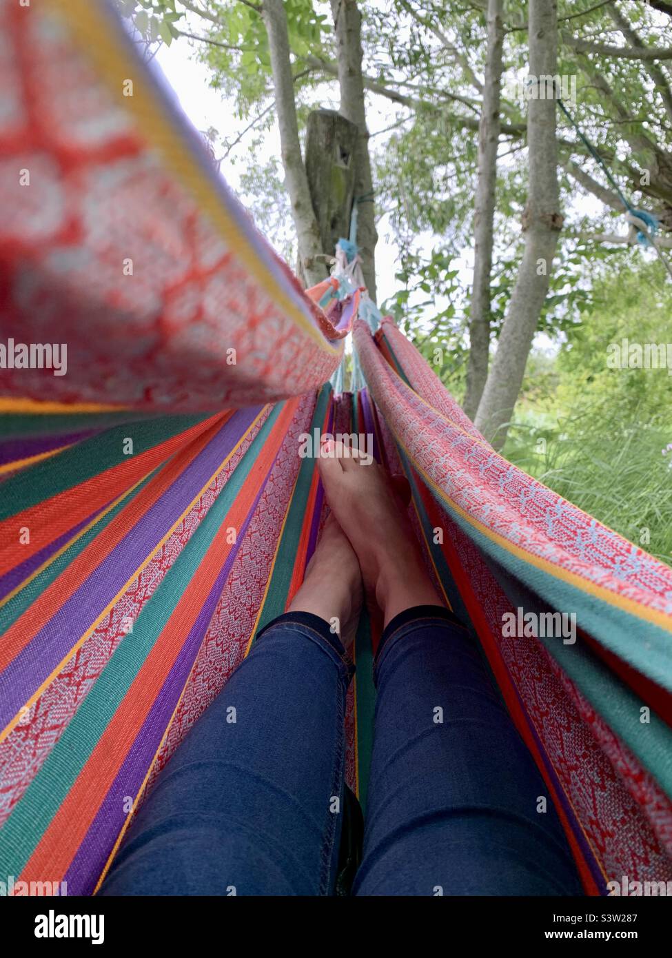 View of legs and feet laying in a colourful hammock Stock Photo - Alamy