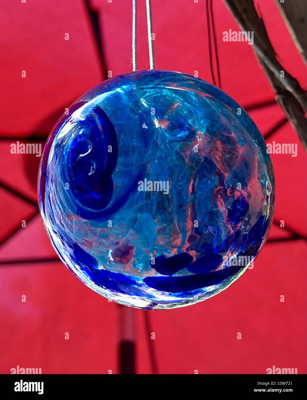 Abstract blue glass ball against a red background Stock Photo - Alamy