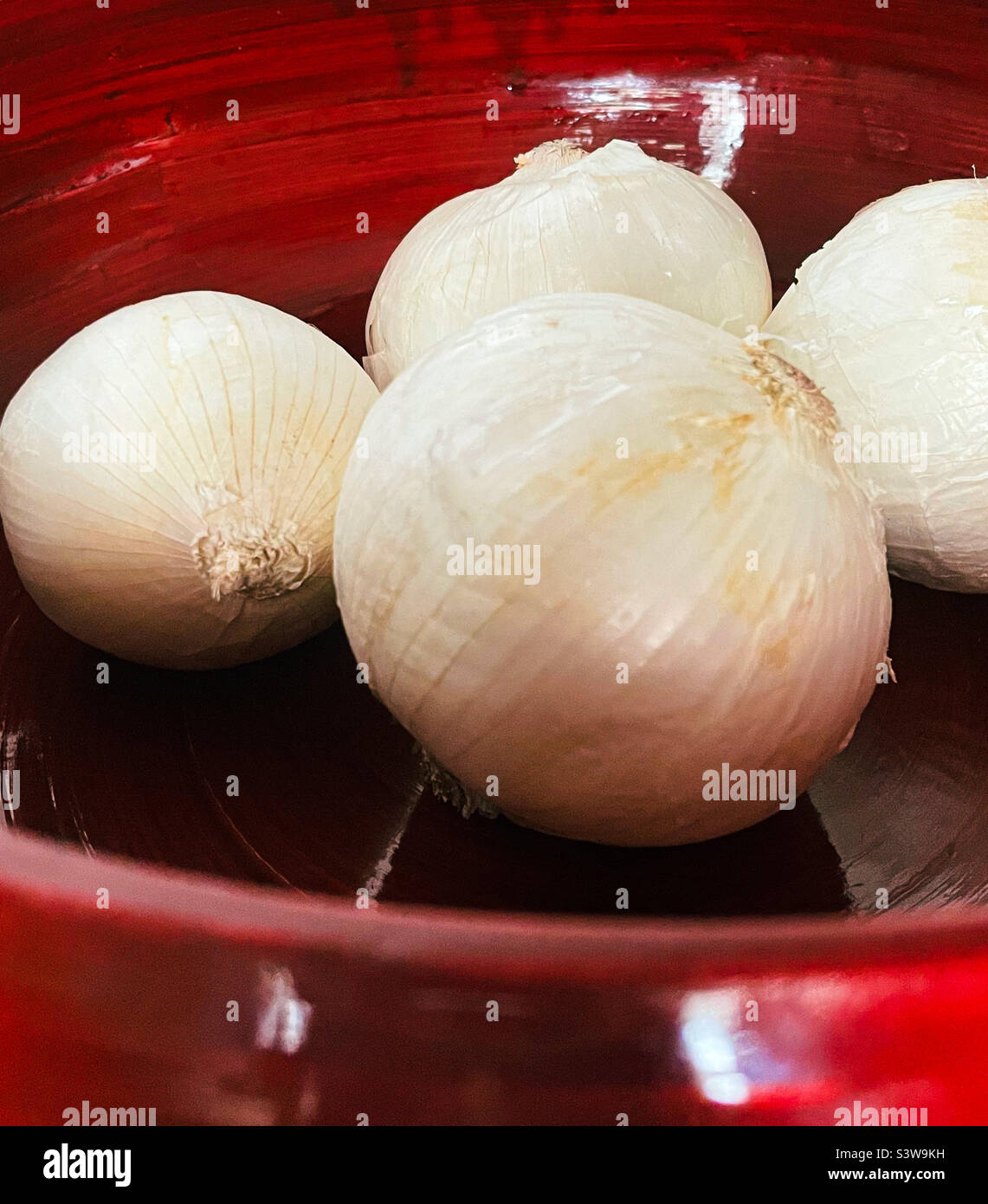 A collection of white onions in a bold red bowl Stock Photo - Alamy