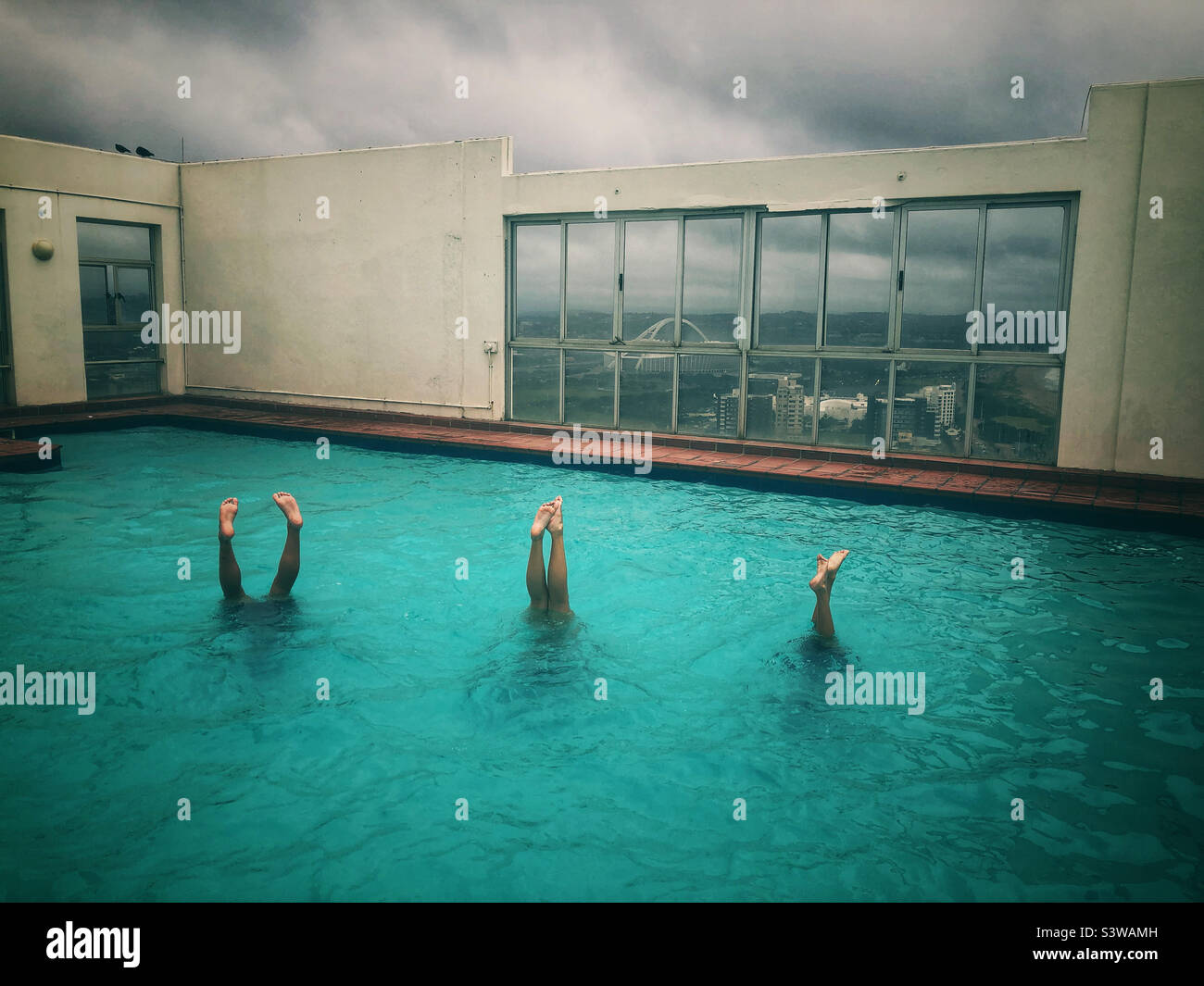 3 Children doing underwater handstands in a rooftop hotel pool Stock ...