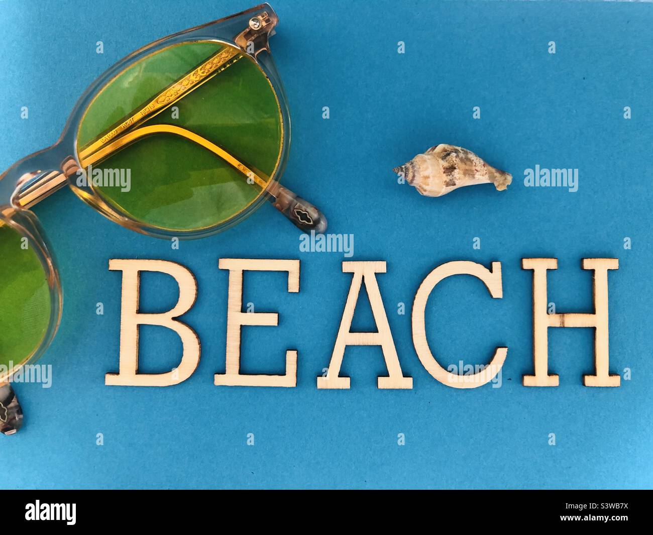 “BEACH” typography, shell and sunglasses on blue black ground Stock ...
