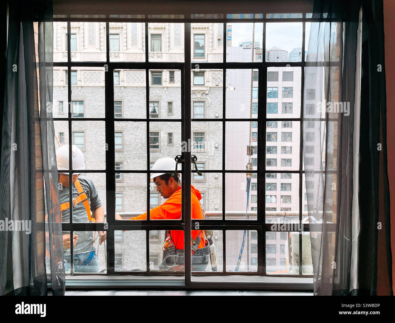 Workers applying waterproofing to the outside of apartment house ...