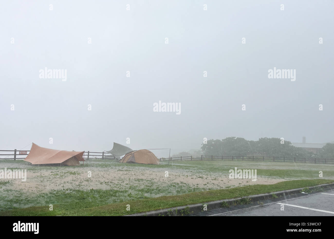 Tents in a flooded clifftop campsite during a large storm. Shosanbetsu ...